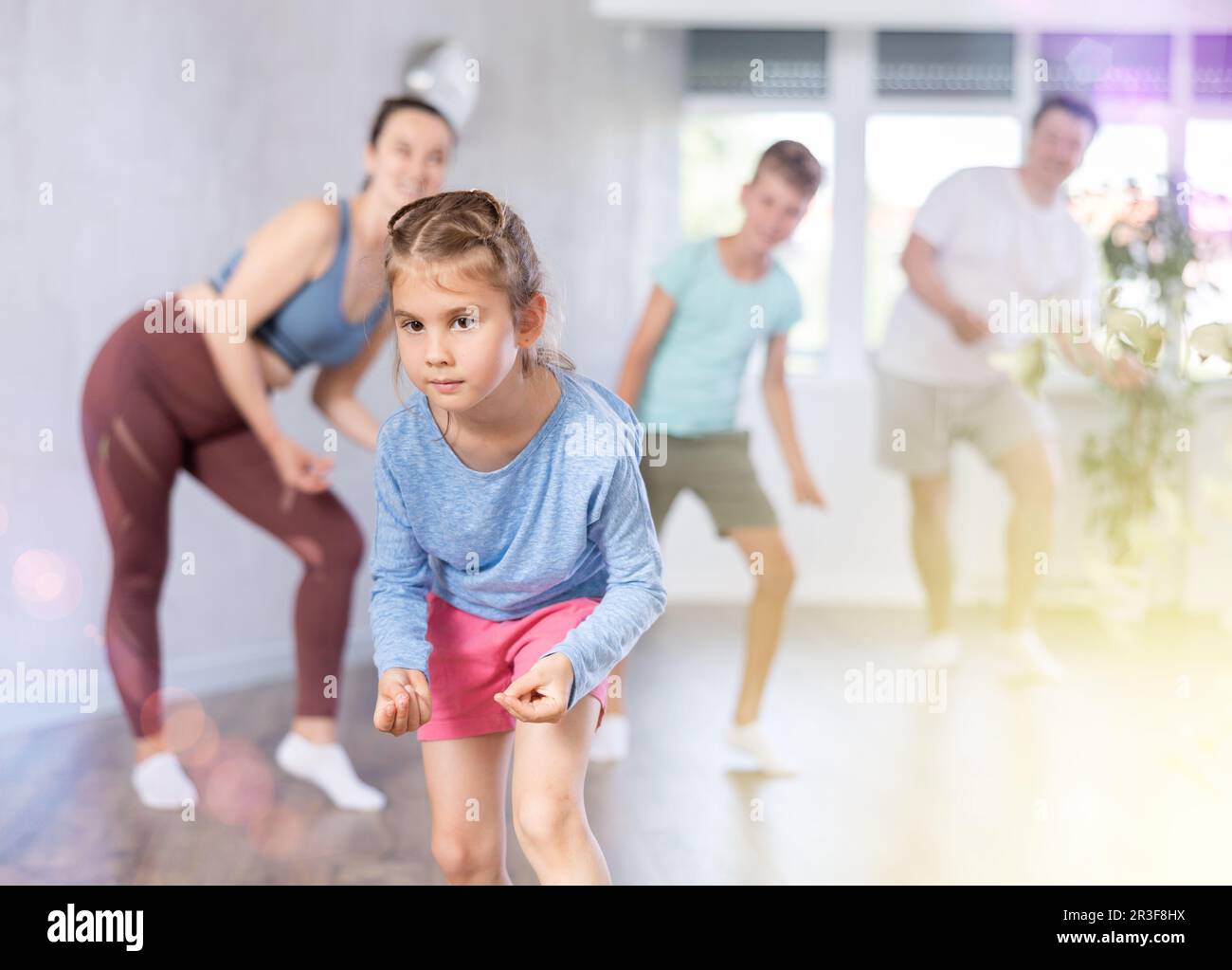Cute little girl practicing dance movements with her family members ...