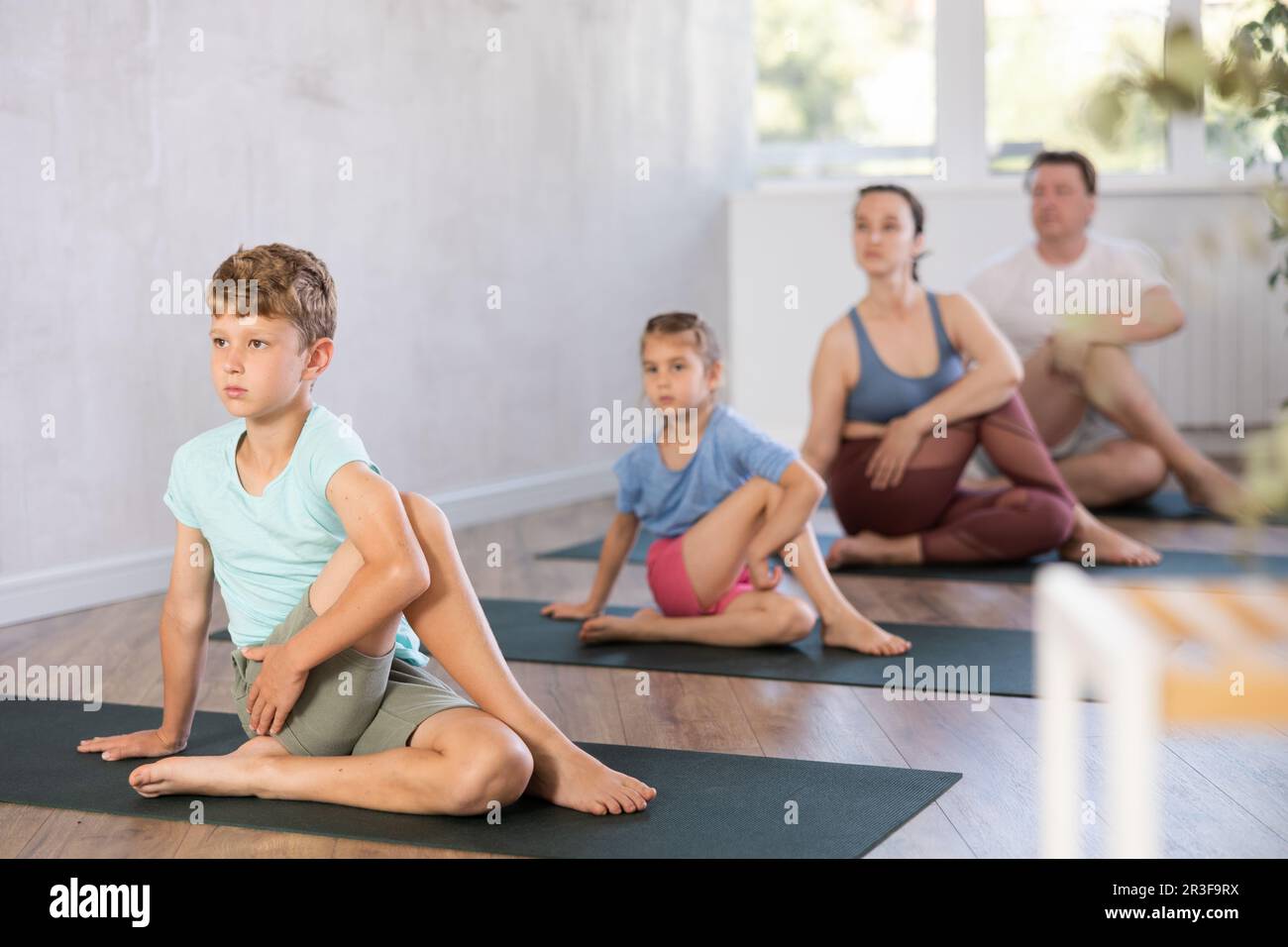 Family with two children doing yoga in studio Stock Photo - Alamy