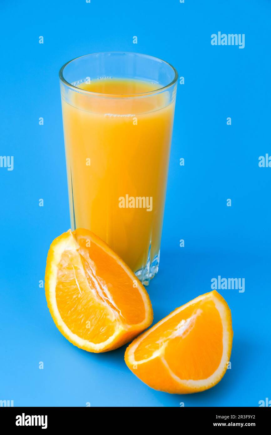 Glass bottle of fresh squeezing Orange juice with sliced fruits on blue ...