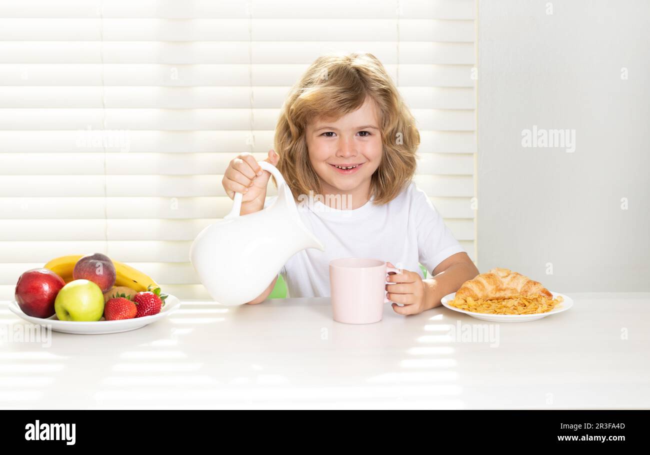 Cute child pouring whole cows milk. Kid preteen boy in the kitchen at ...