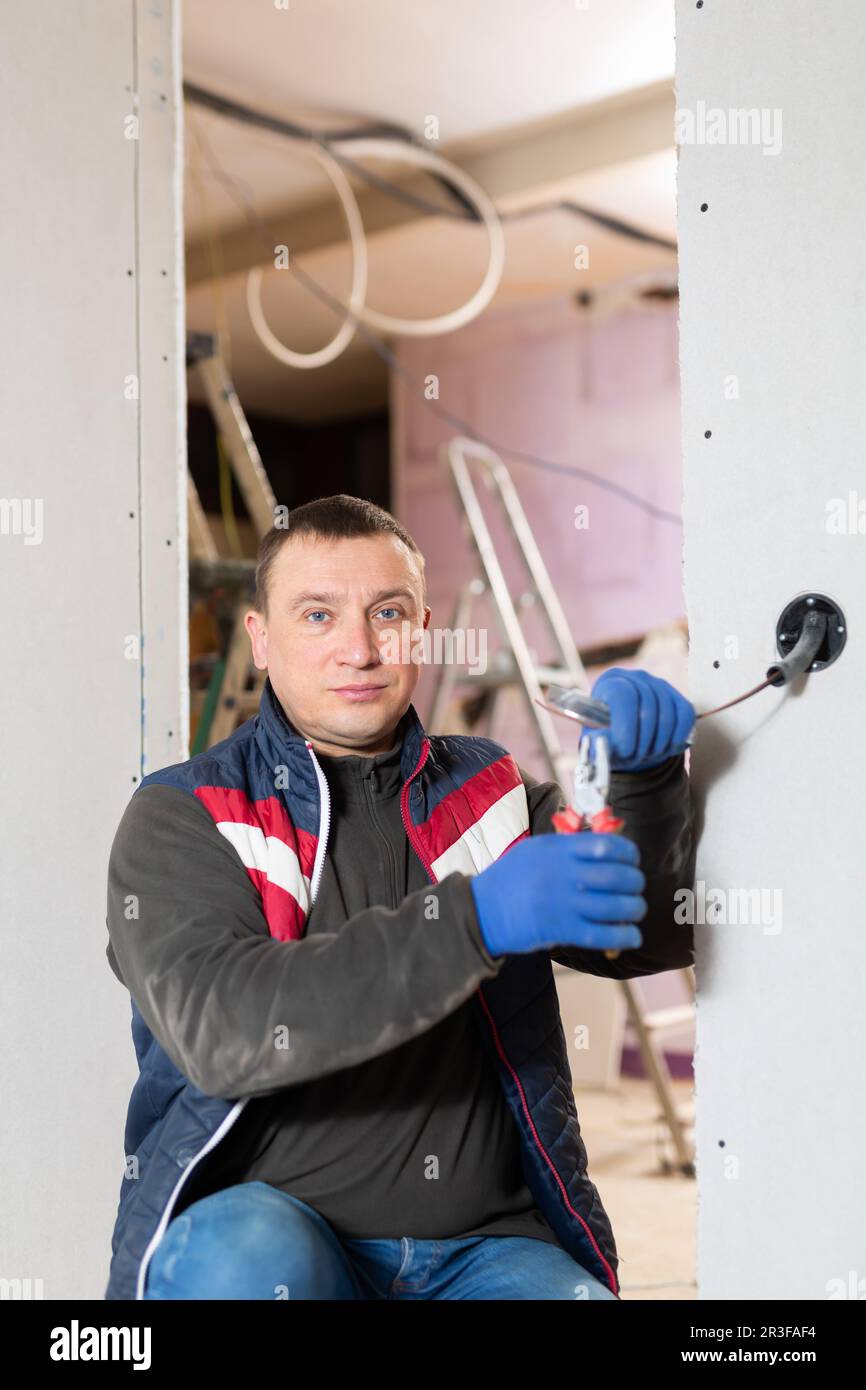 Professional builder engaged in electrical installation work at indoors ...