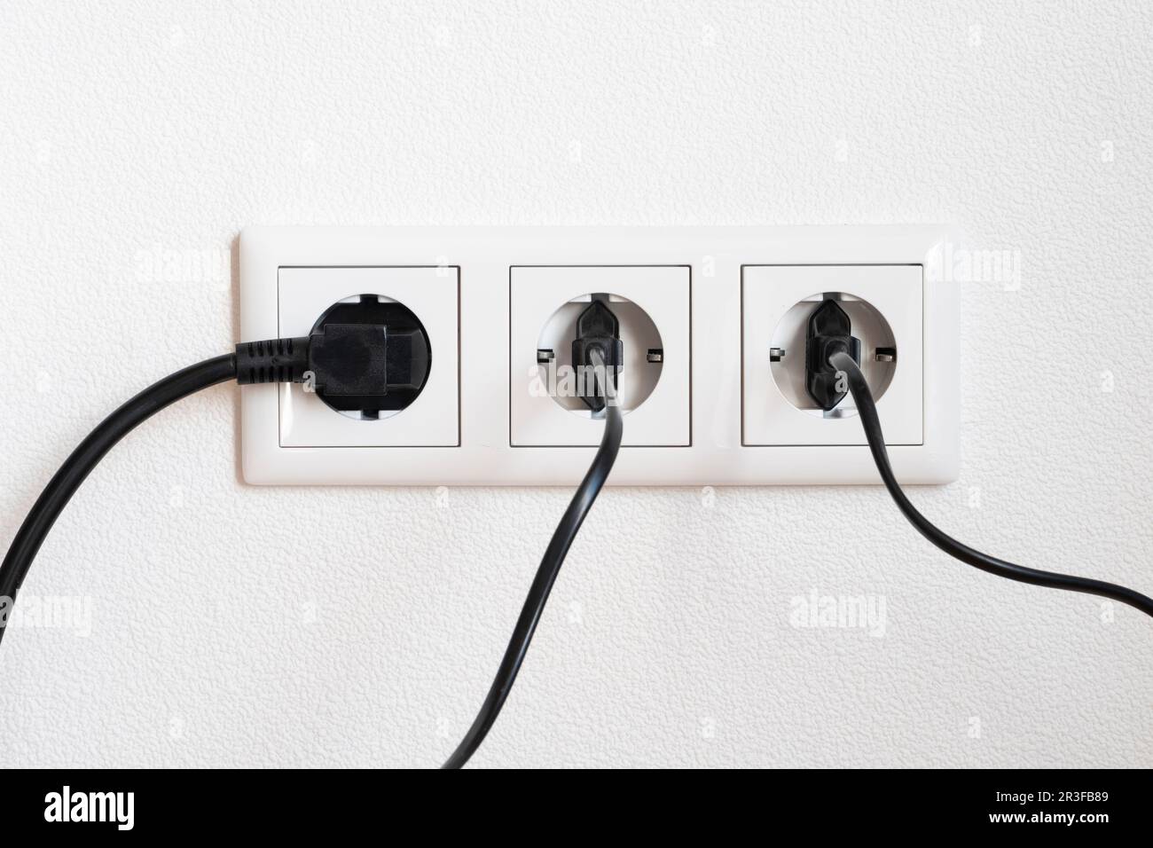 Three cable at a triple socket Stock Photo - Alamy
