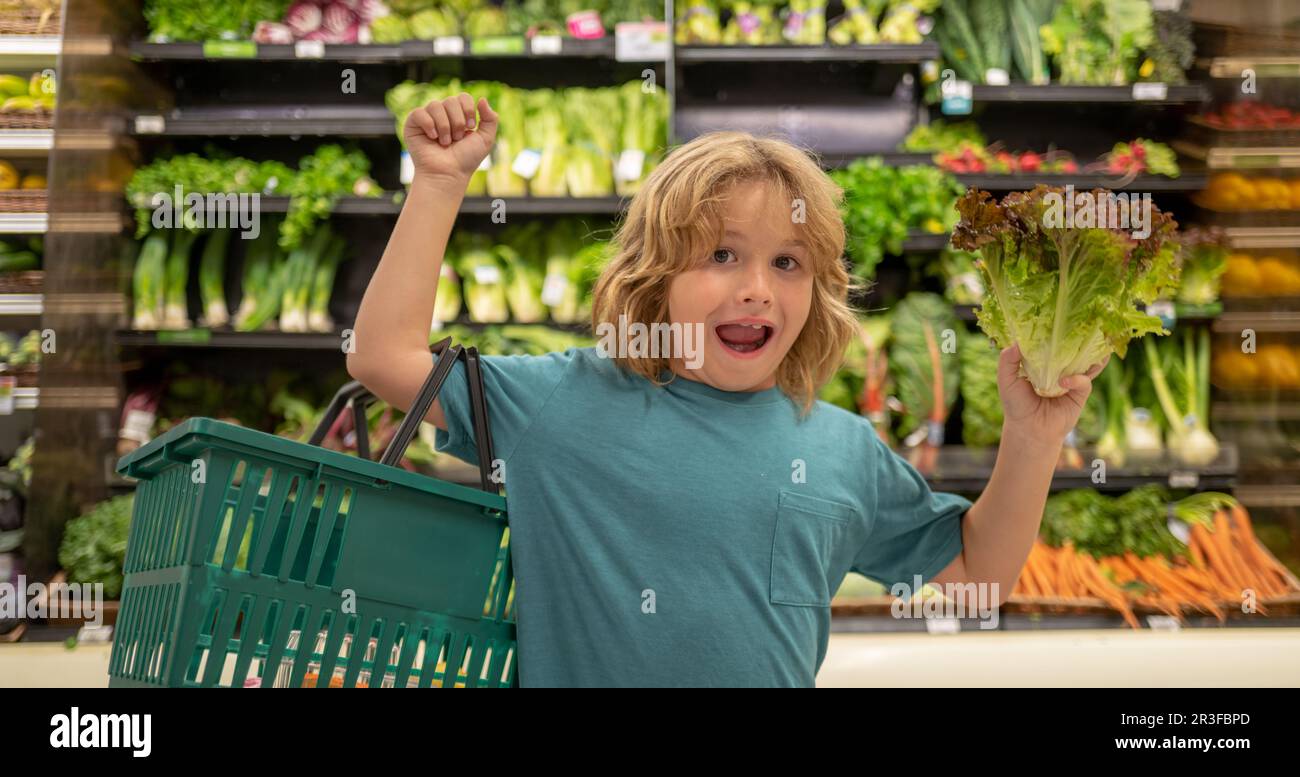 Child with lettuce salad. Shopping in supermarket. Kids buying ...