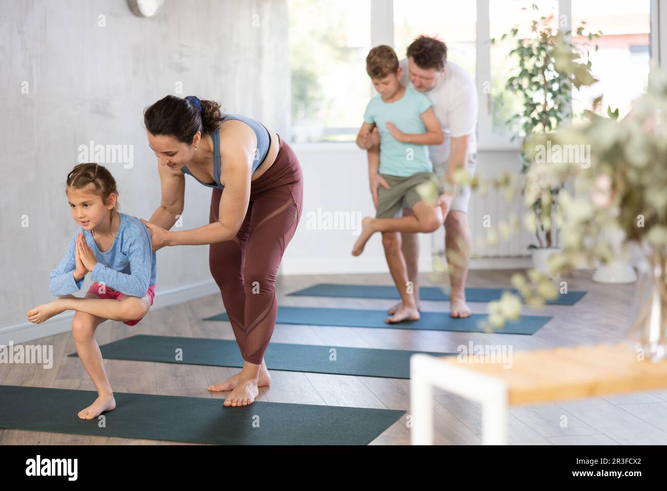 Careful parents helping their son and daughter to make chair pose Stock ...