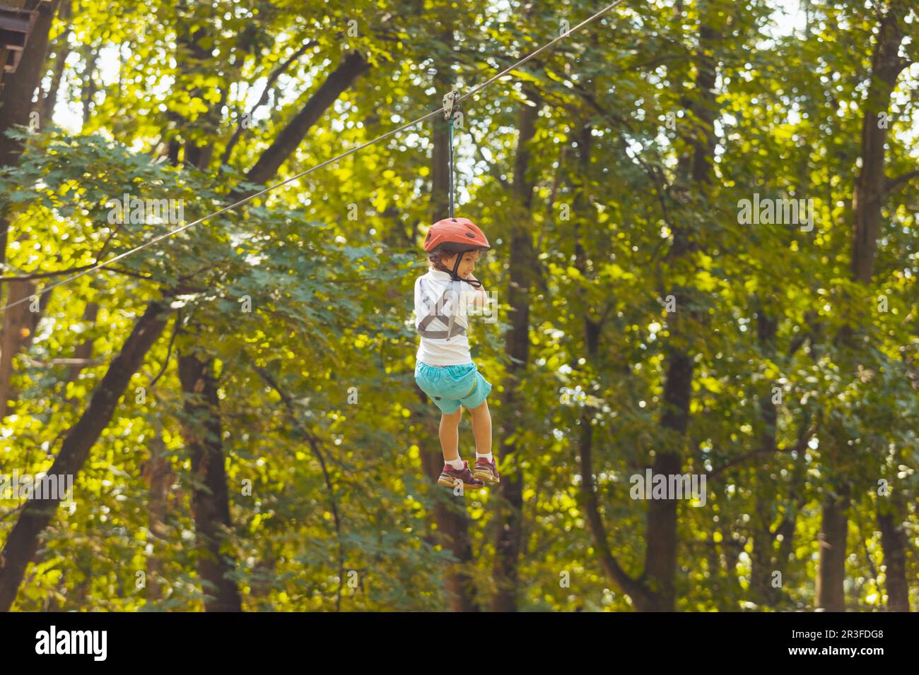 The little boy goes down the zipline in the park Stock Photo - Alamy