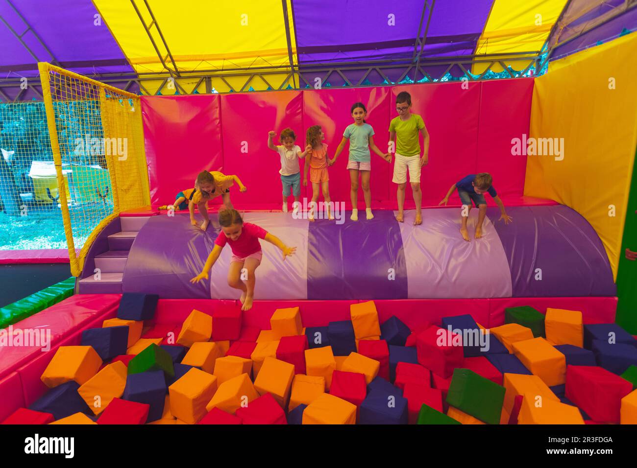 The happy little kids are jumping into dry pool with soft cubes. The ...