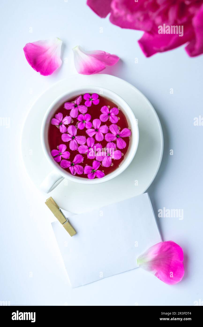 Creative layout with pink peonies flowers and cup of tea on bright ...