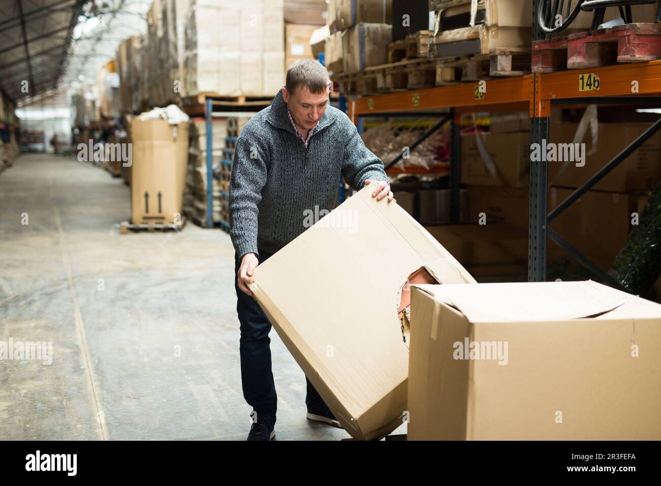 Male seller holding box in warehouse Stock Photo - Alamy