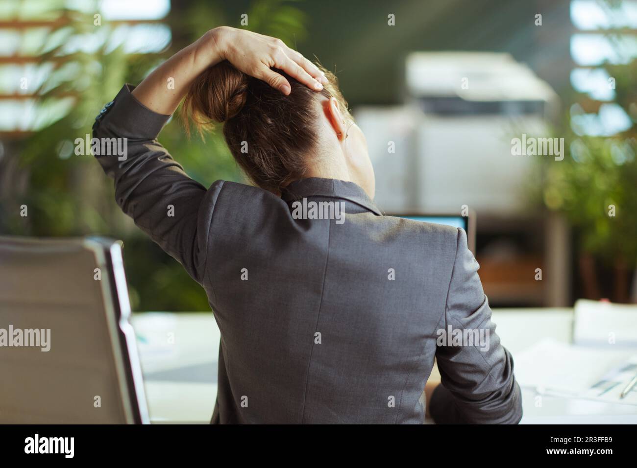 Sustainable workplace. Seen from behind modern business woman in a grey ...