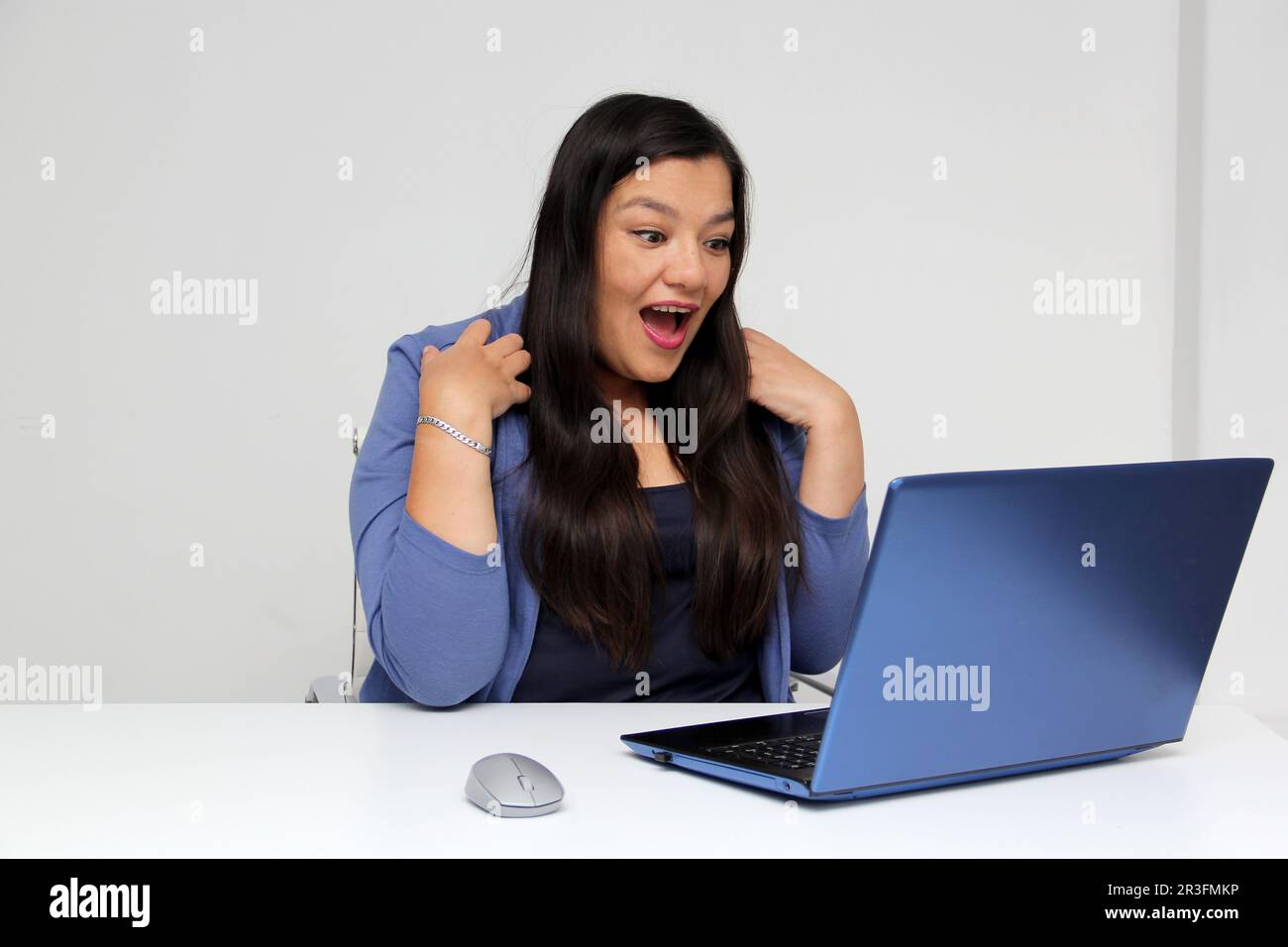 Latin adult woman works on her laptop in her office, celebrates and is ...