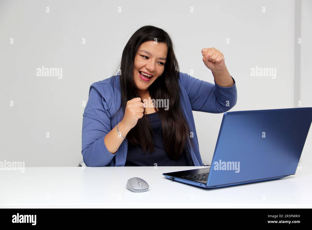 Latin adult woman works on her laptop in her office, celebrates and is ...