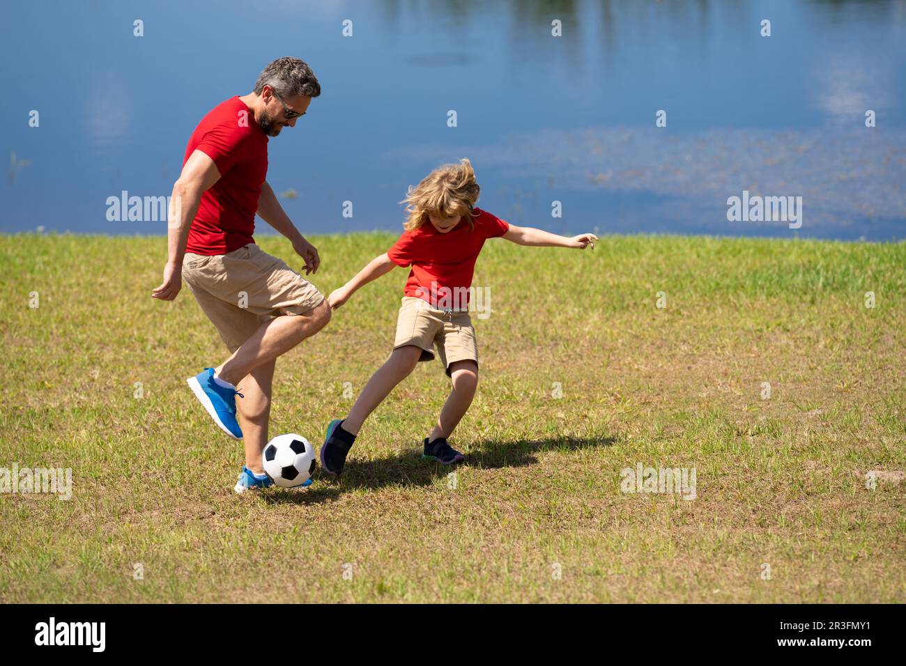 Father and son enjoy a friendly game of football. Practice passing and ...