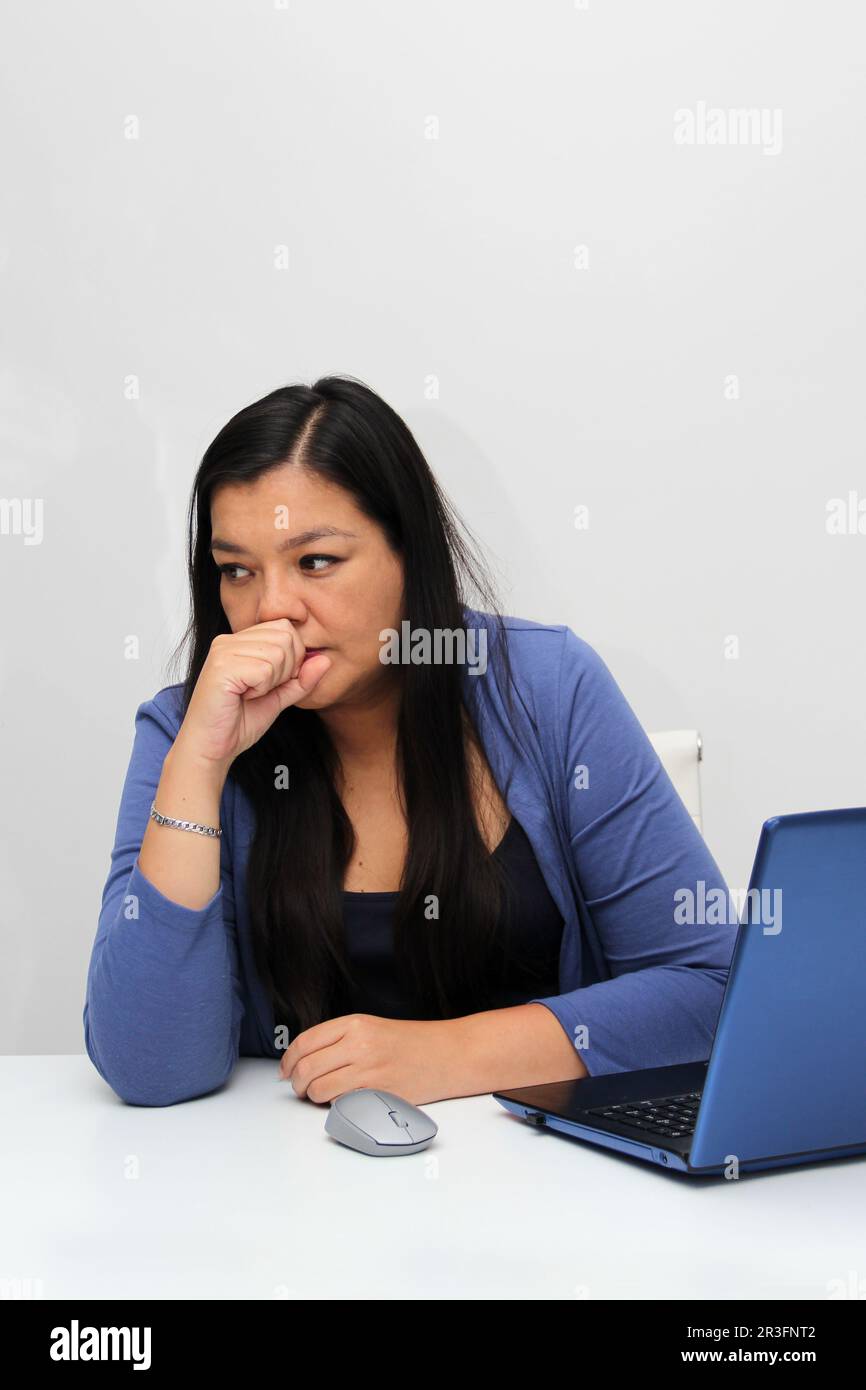 Forty-year-old adult Latina woman works in her office with her laptop, she is desperate and ...