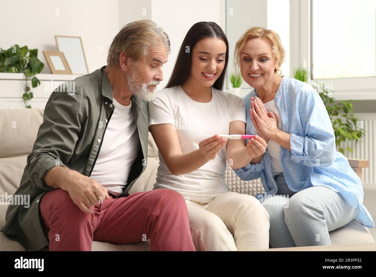 Happy woman showing her parents pregnancy test at home. Grandparents ...