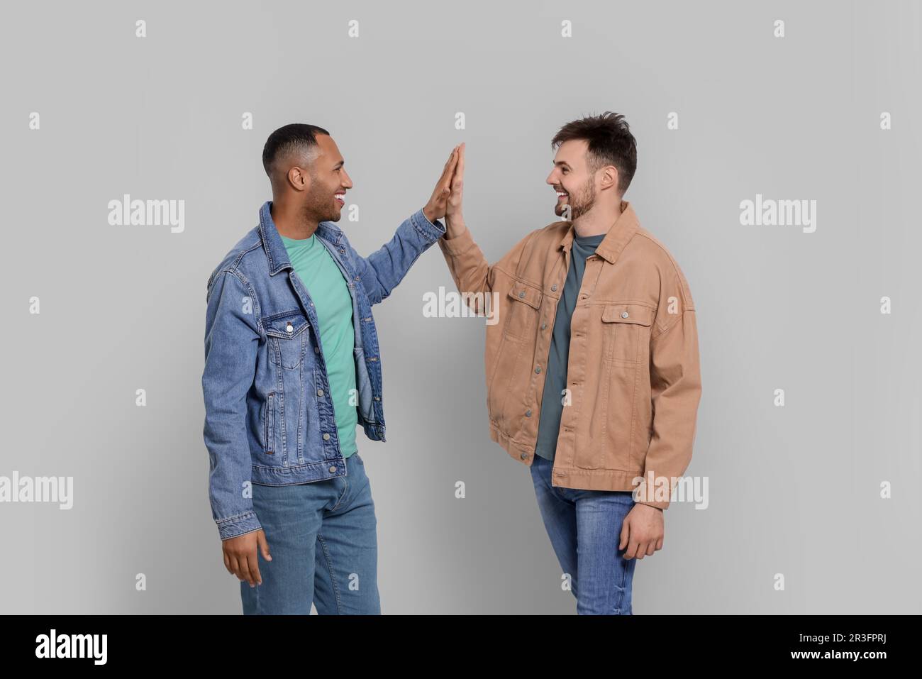 Men giving high five on grey background Stock Photo - Alamy