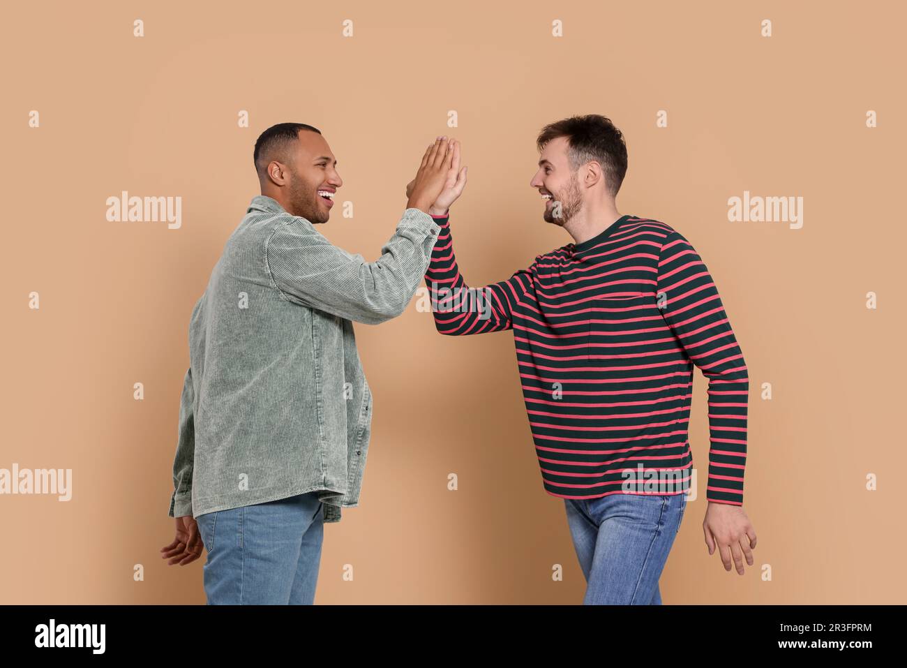 Men giving high five on beige background Stock Photo - Alamy