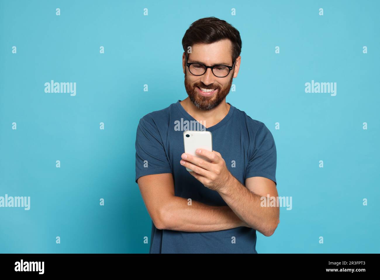 Happy man looking at smartphone on light blue background Stock Photo ...