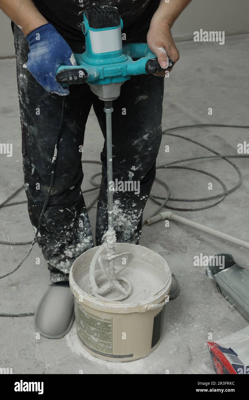Professional worker mixing plaster in bucket indoors, closeup Stock ...