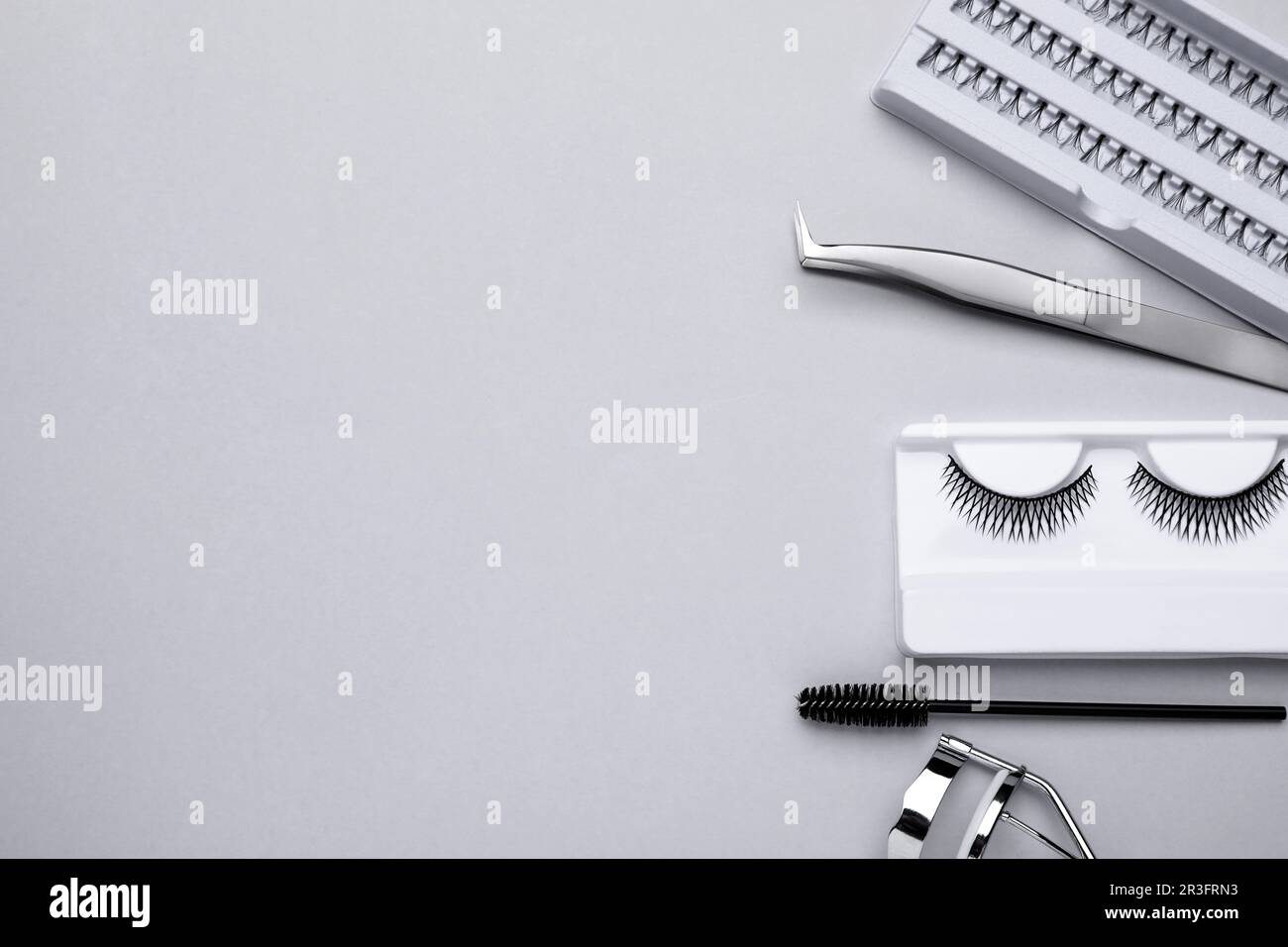 Flat lay composition with fake eyelashes, brush and tools on light grey ...