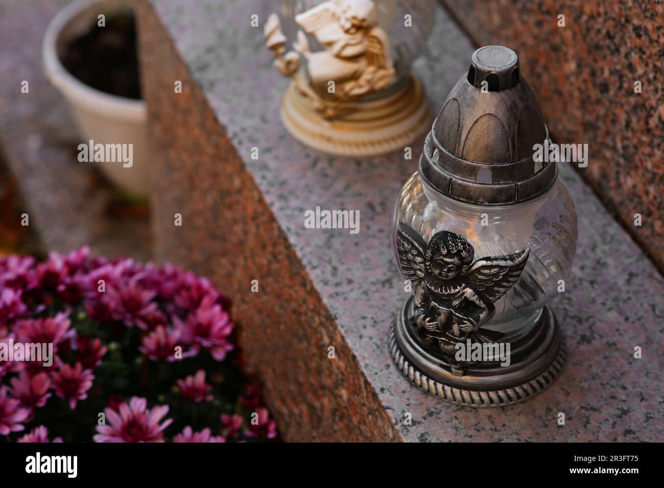 Grave lanterns and flowers on granite surface in cemetery Stock Photo - Alamy