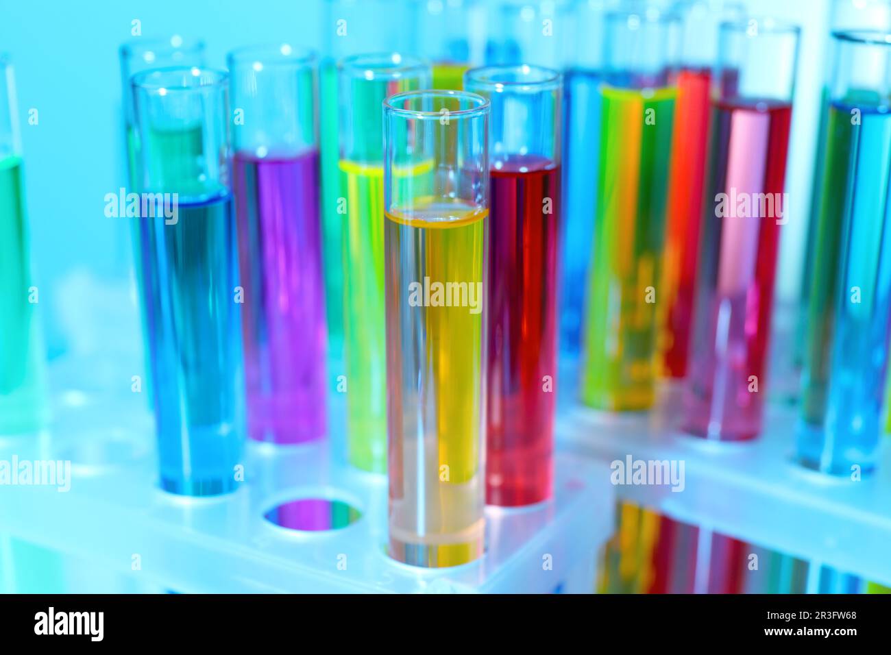 Many test tubes with colorful liquids on blurred background, closeup ...
