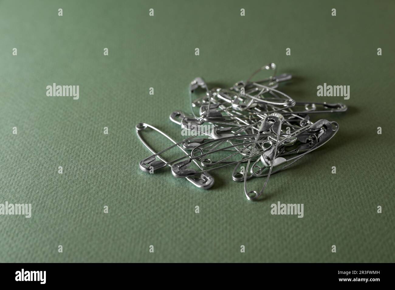 Pile of safety pins on green background, space for text Stock Photo - Alamy