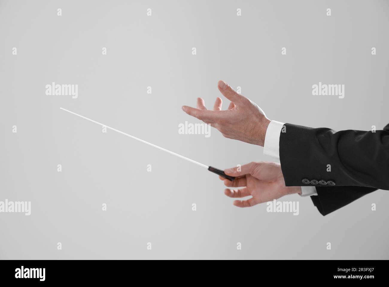 Professional conductor with baton on light grey background, closeup ...