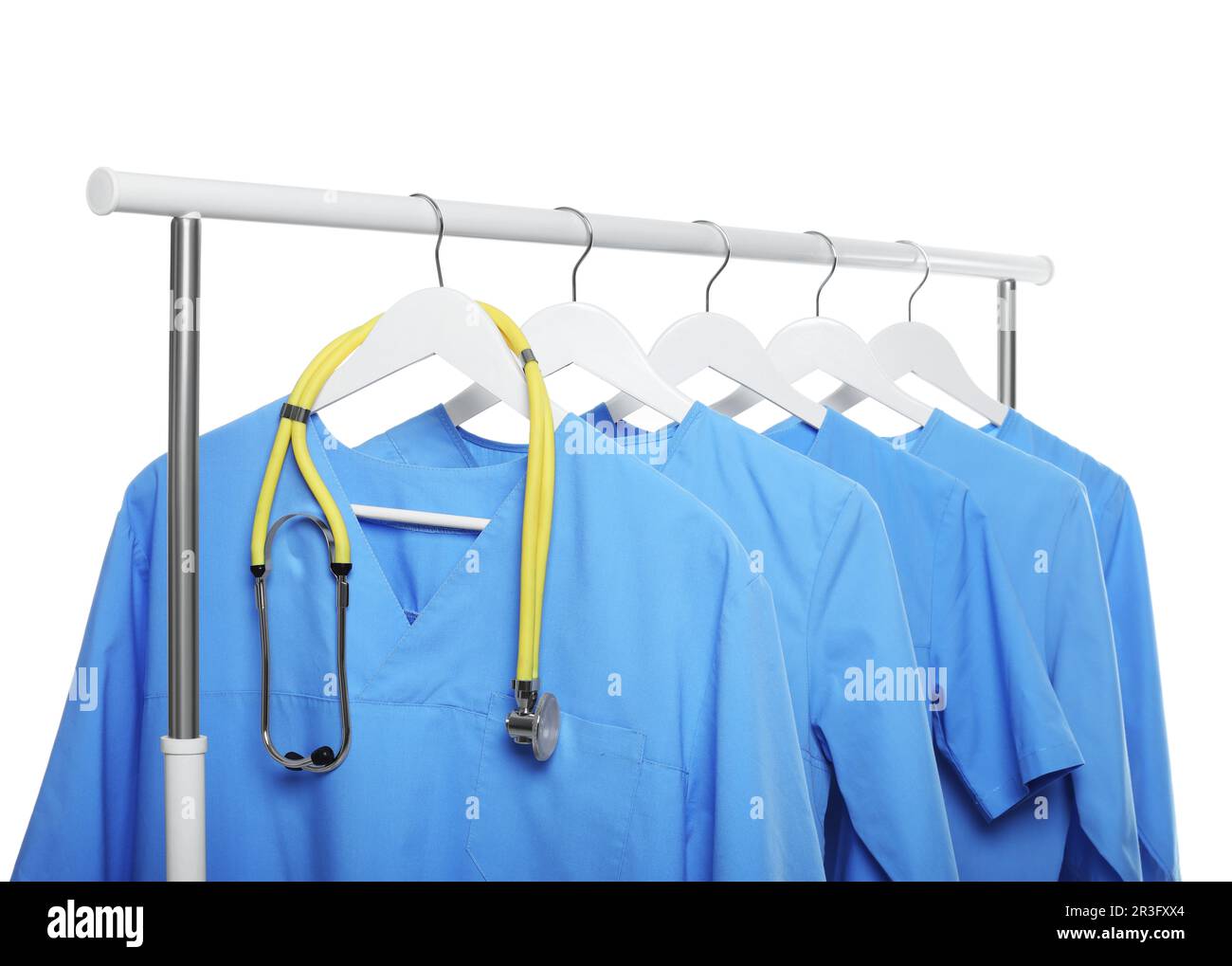 Light blue medical uniforms and stethoscope on rack against white ...