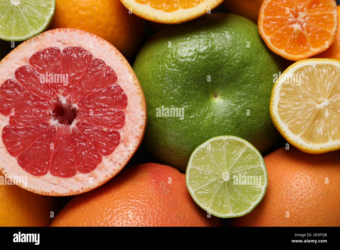 Different fresh whole and cut citrus fruits as background, top view ...