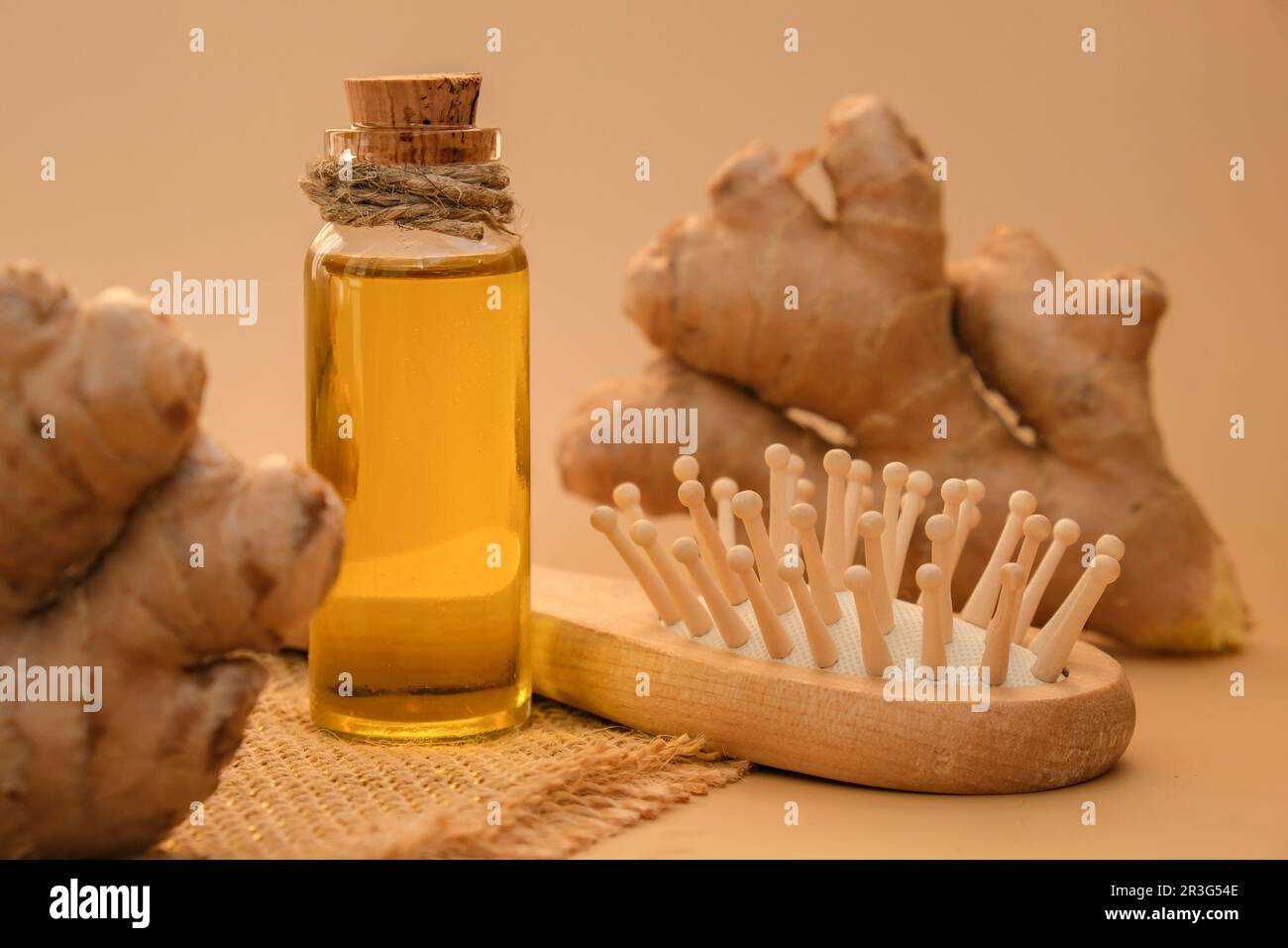 Glass bottle of essential ginger oil, ginger root on beige background ...