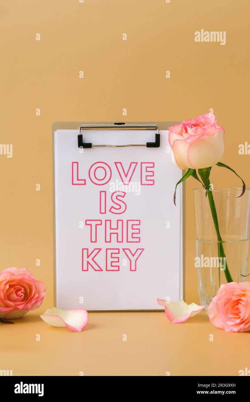 LOVE IS THE KEY text on greeting card paper note. Delicate pink roses ...