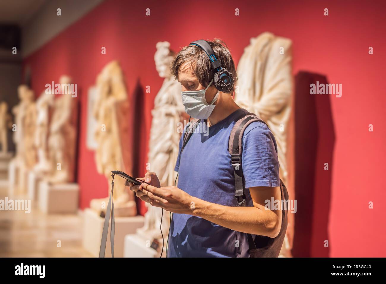 Portrait of contemporary man looking at sculptures and listening to ...