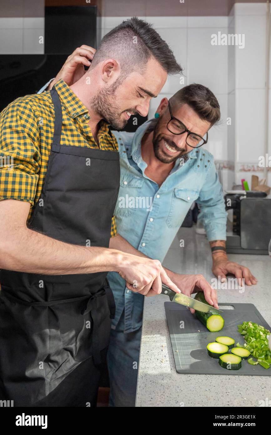 Happy hipster gay couple in love standing in the kitchen. They are ...
