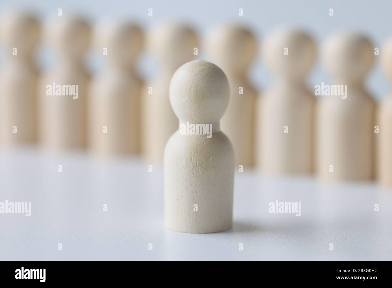 White wooden figure stands against blurred figurines in row Stock Photo ...