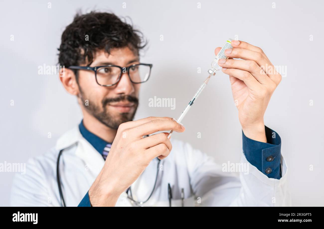 Handsome Doctor drawing medicine from a vial isolated. Young doctor ...