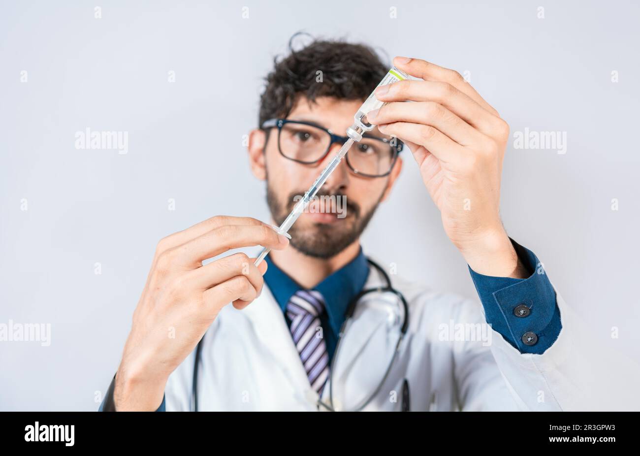 Doctor drawing medicine from a vial isolated. Young doctor drawing ...