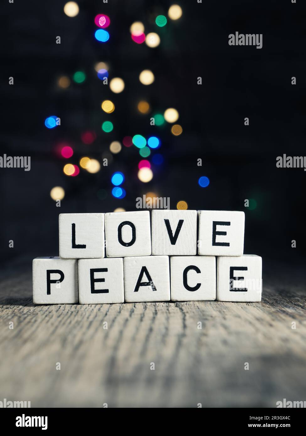 Wooden cube with inscription love and peace, blurred lights in the ...