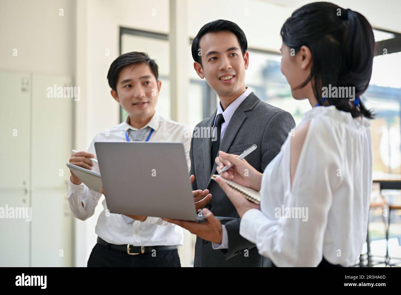 A professional Asian male boss listens to his female employees opinions ...