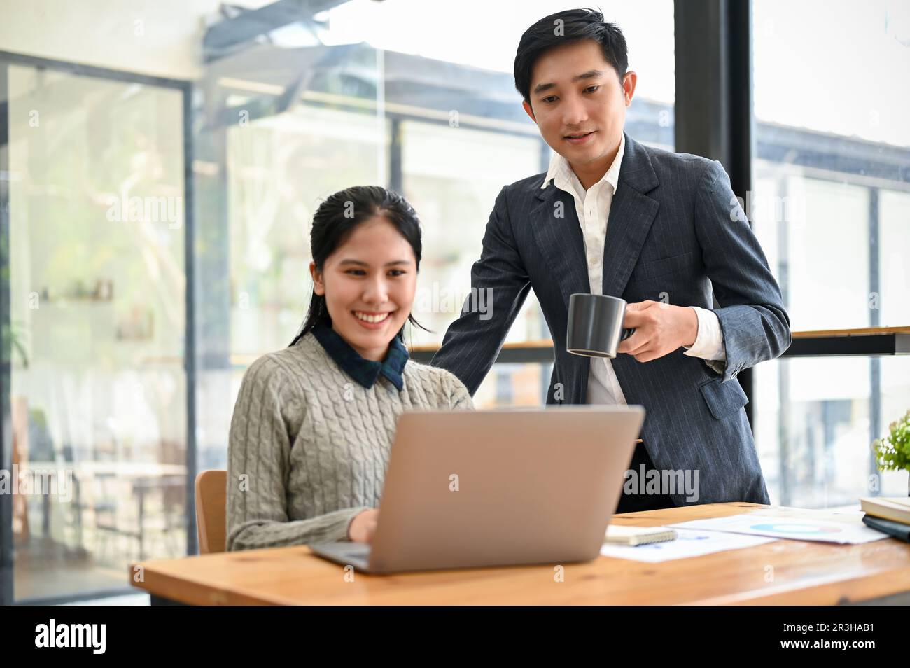 A professional Asian male boss coaching a new young female employee in ...