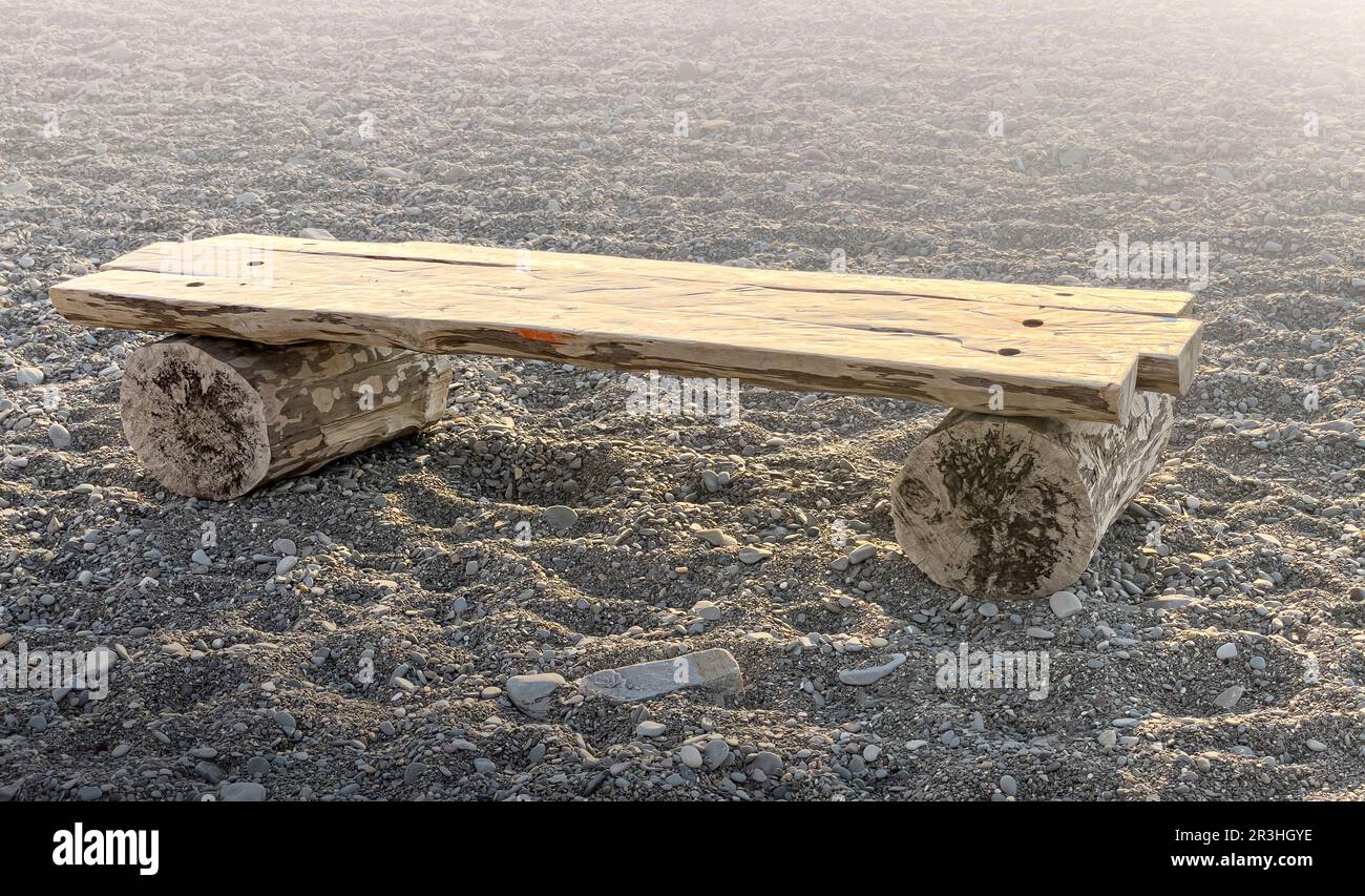 A bench made of a log for relaxation. stone coast Stock Photo - Alamy