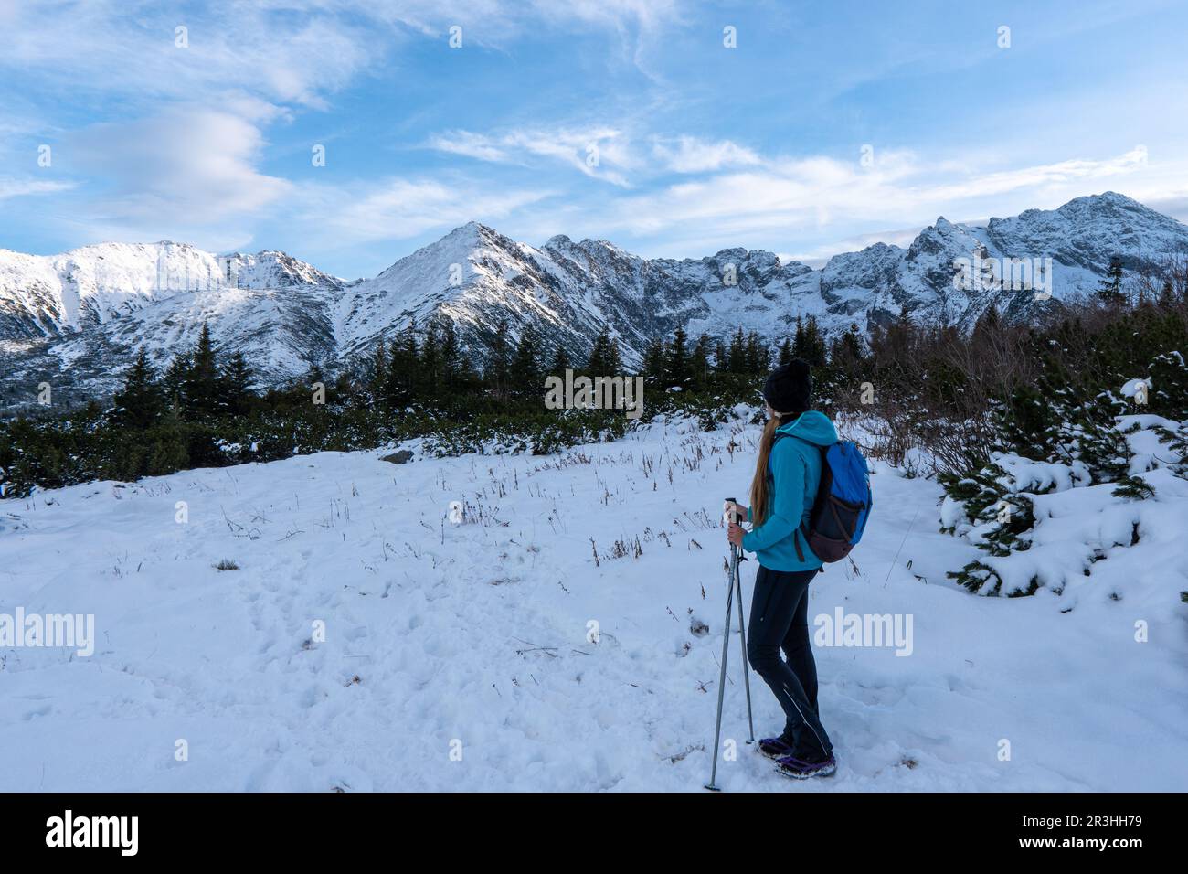 Hiker woman standing and looks around, admiring winter mountain ...