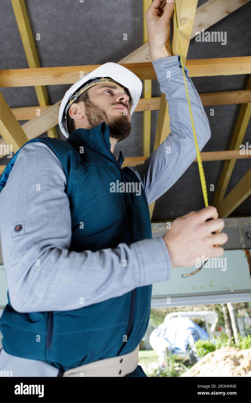 man measuring metal bar in roof space Stock Photo - Alamy