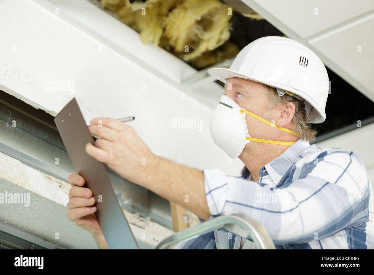 male technician wearing mask looking at ceiling and taking notes Stock ...