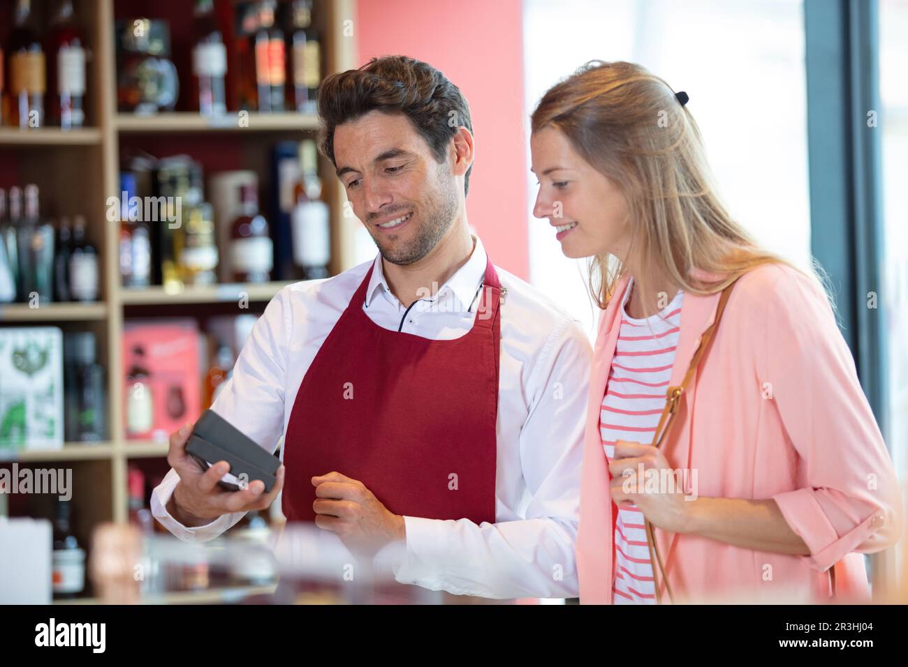 man seller helping woman customer with a bottle of wine Stock Photo - Alamy