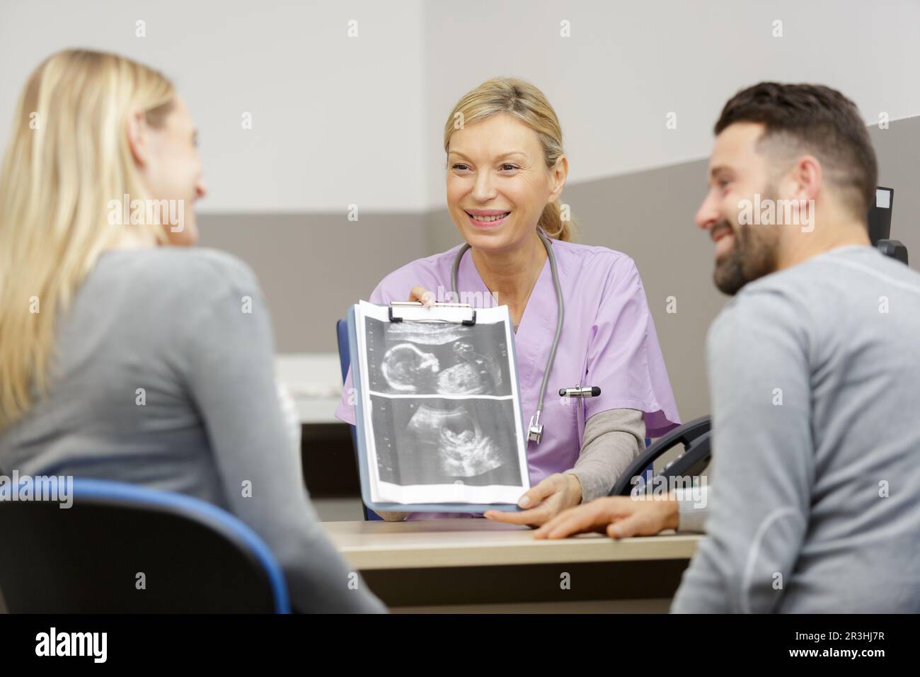 gynecologist showing scan of unborn baby to happy couple Stock Photo ...