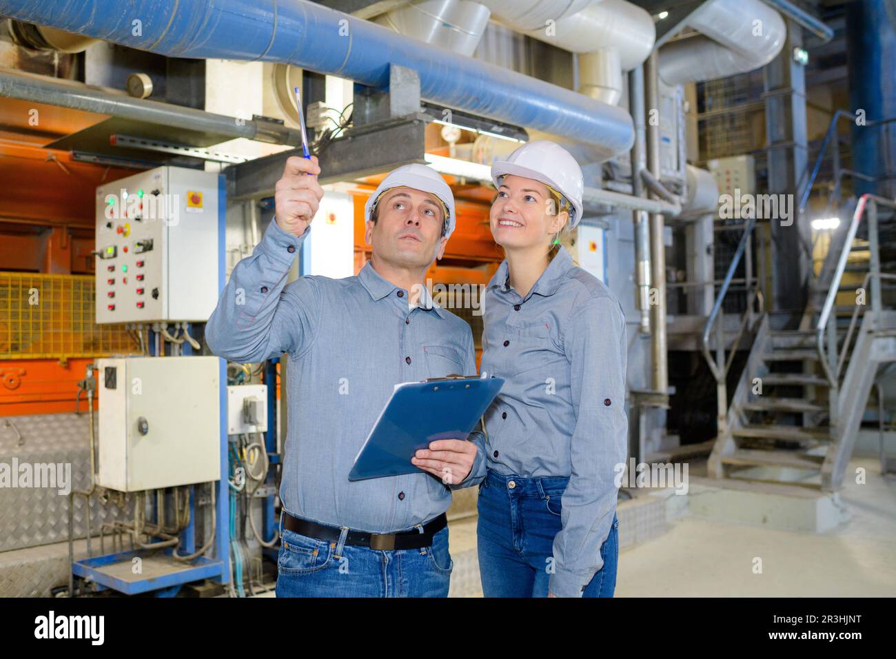industrial pipe maintenance worker showing apprentice Stock Photo - Alamy