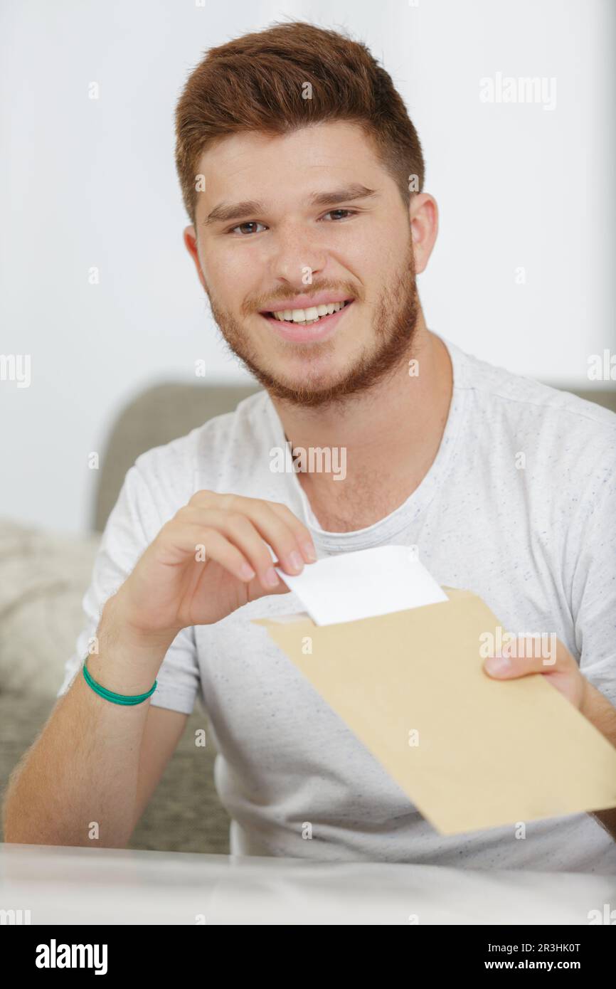 young man pulling letter from envelope Stock Photo - Alamy