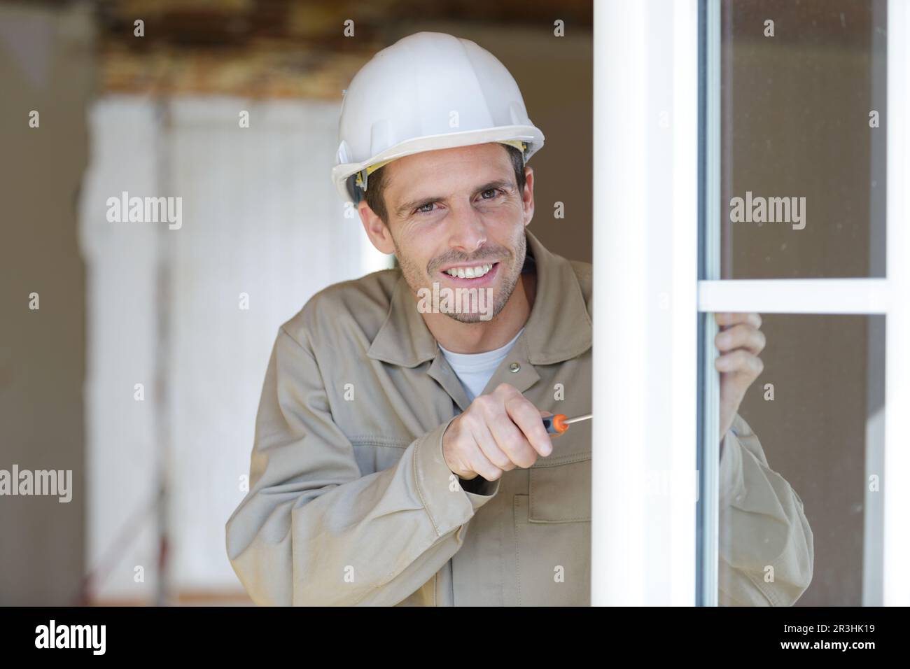 window fitter using screwdirver on window frame Stock Photo - Alamy