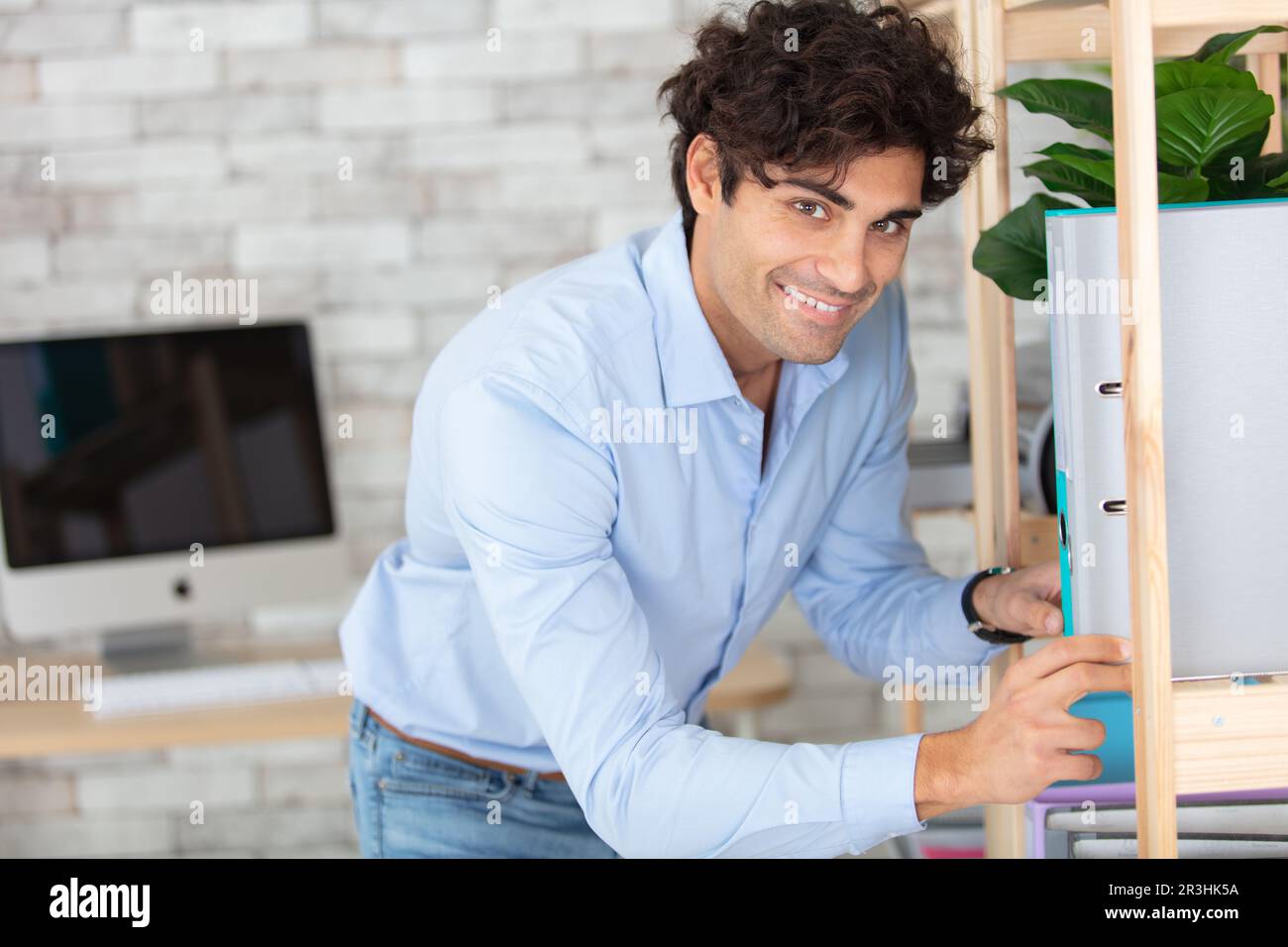 young man standing next to the shelf with folders Stock Photo - Alamy