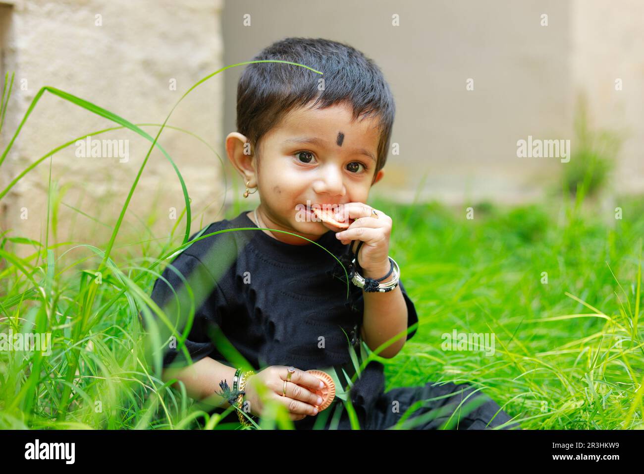 kid playing outside and eating cookies or biscuit in green park ...